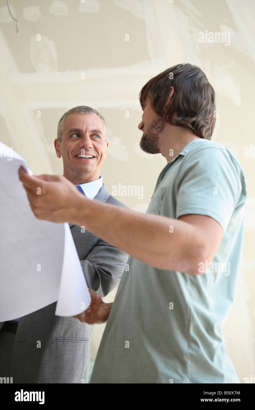 Two men looking at construction plan Stock Photo - Alamy