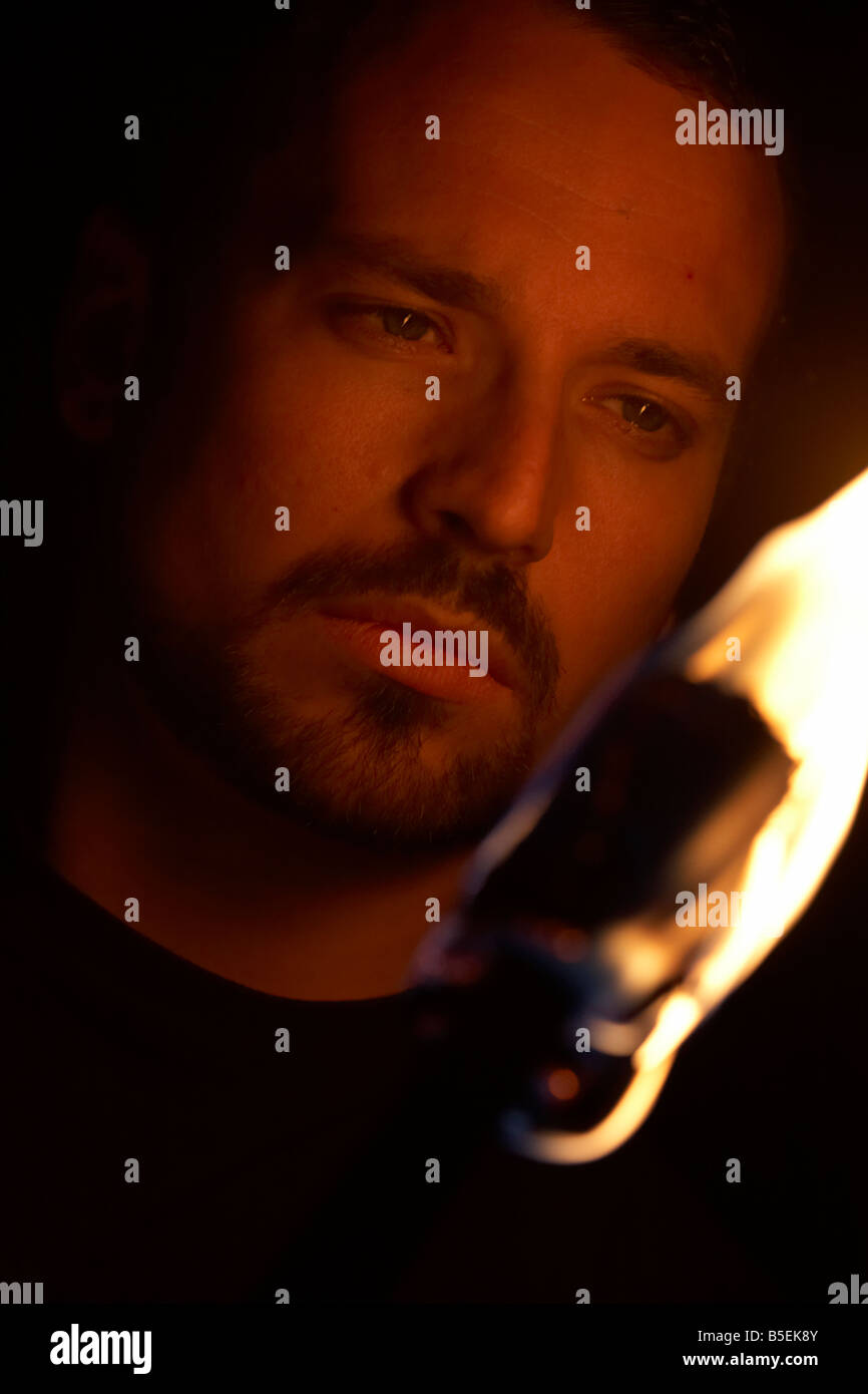 firepoise man looking through flames of burning torch playing with fire ...