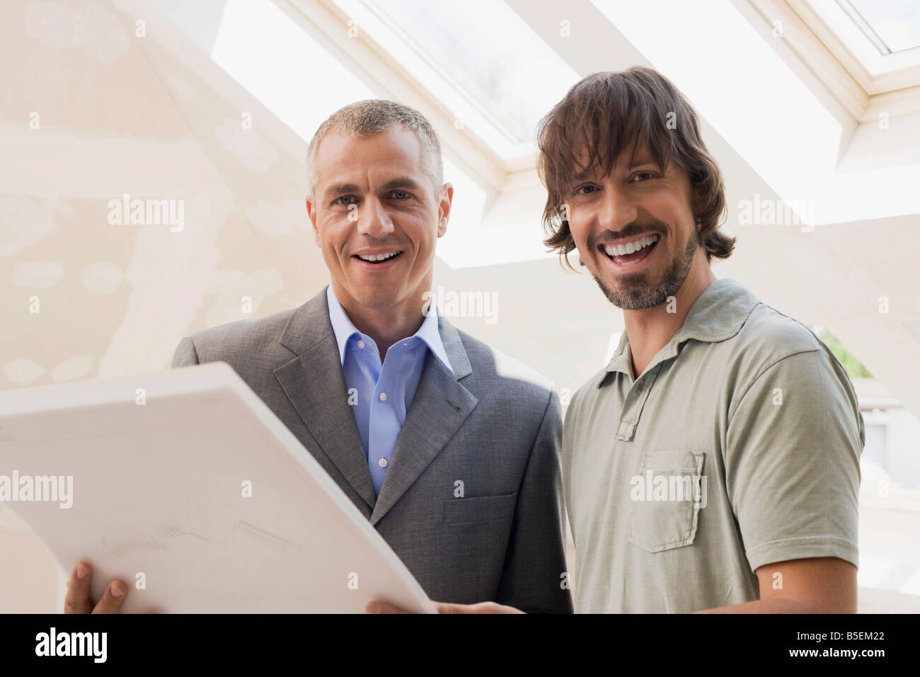 Two men with construction plan, smiling, portrait Stock Photo - Alamy