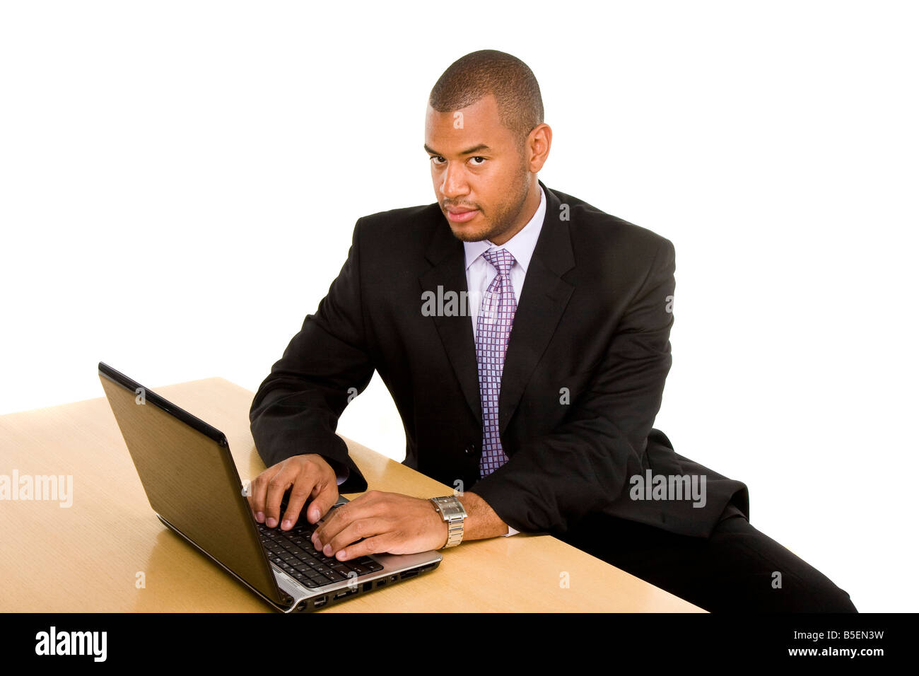 A nice looking black man in a suit sitting at a desk working on a ...