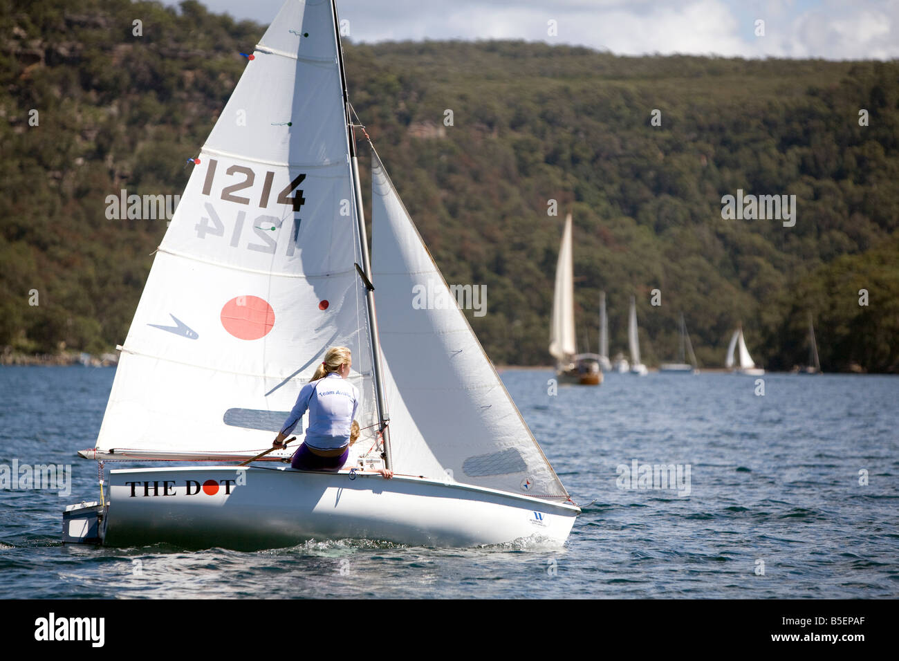 solo handed female sailor leaning out of her dinghy to increase speed ...