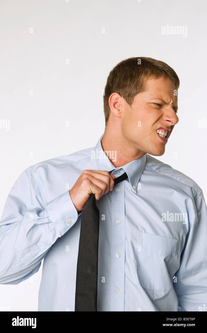 Businessman loosening his tie, looking angry Stock Photo - Alamy