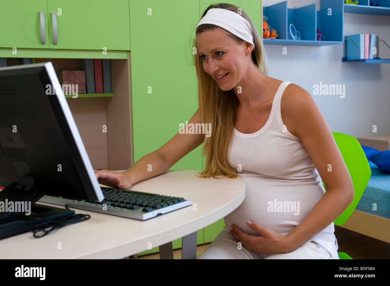 Pregnant woman sitting in front of a computer Stock Photo - Alamy