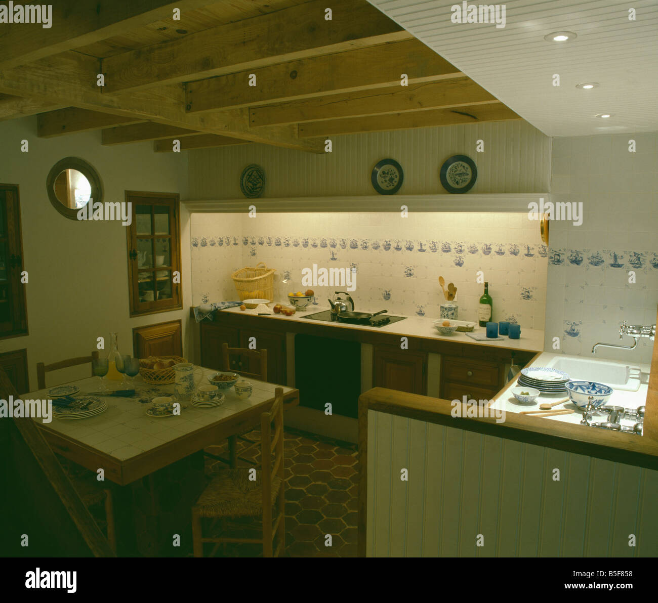 Downlighting above worktop with fitted hob in kitchen with blue tiled ...