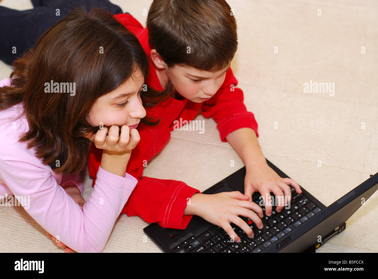 Portrait of brother and sister looking into computer Stock Photo - Alamy