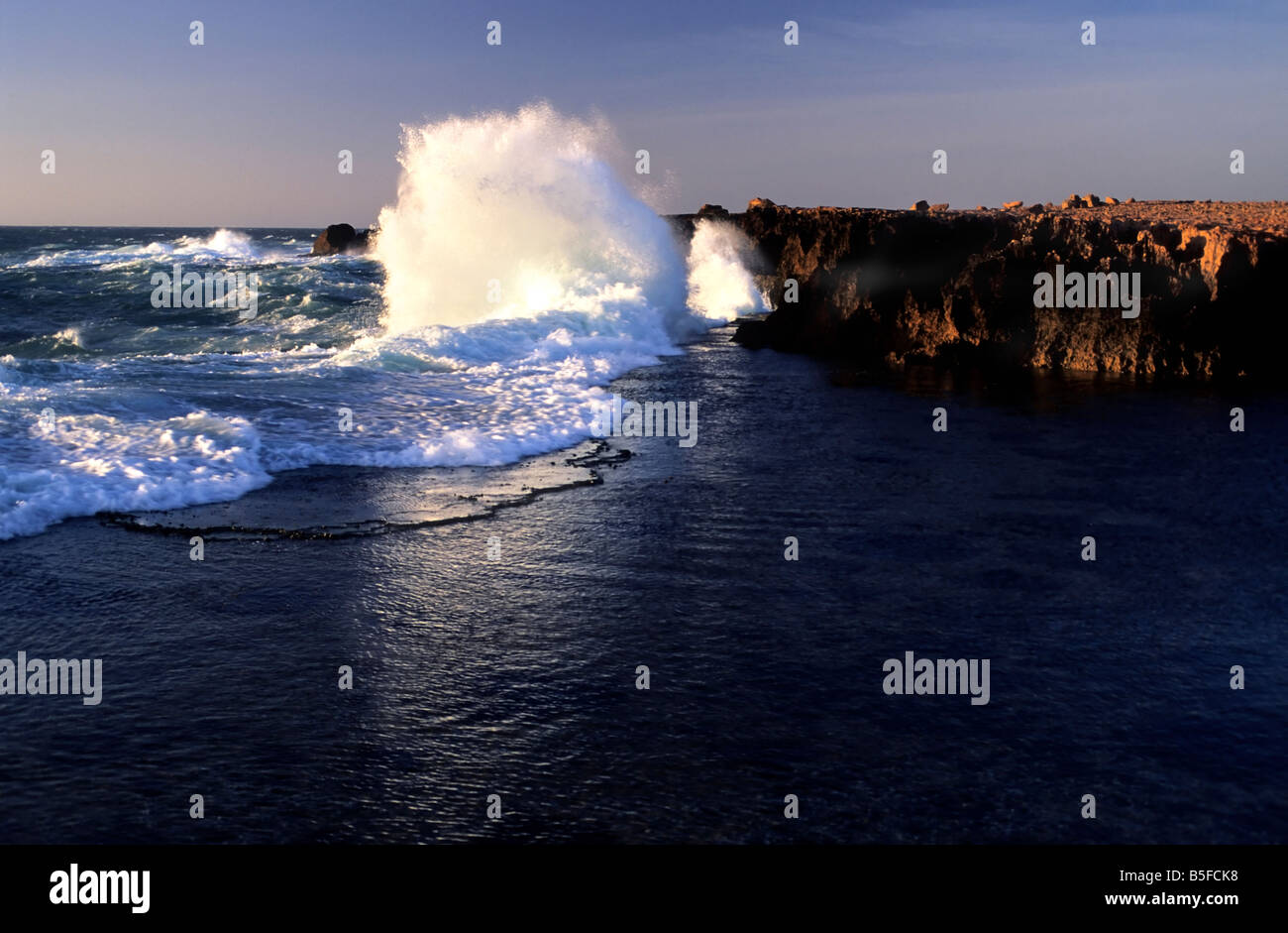 Ocean wave breaking onto rocky coastline at sunset, Point Quobba ...