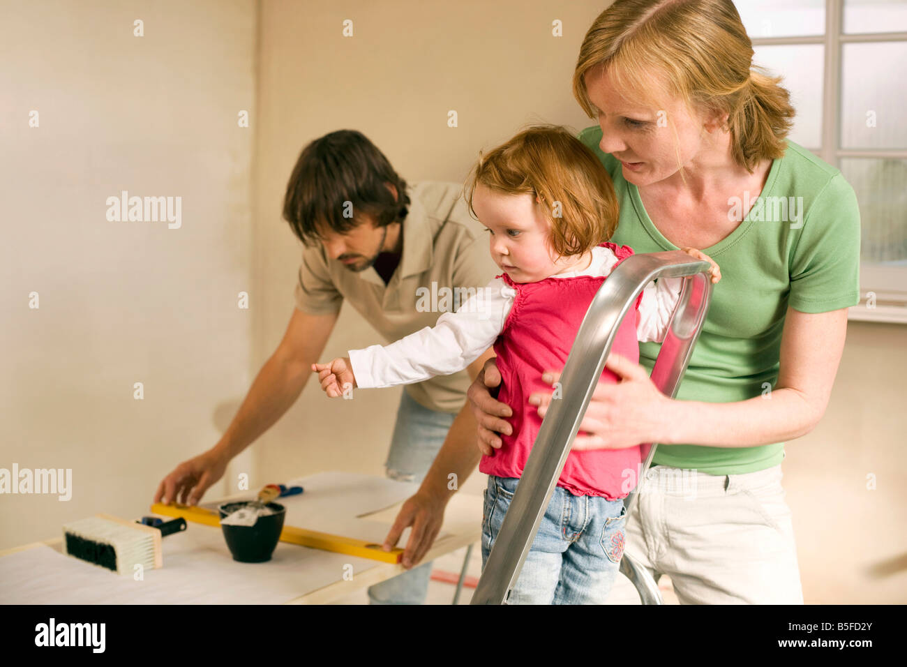 Family, Baby girl (1-2) on step ladder, man preparing wallpaper Stock ...