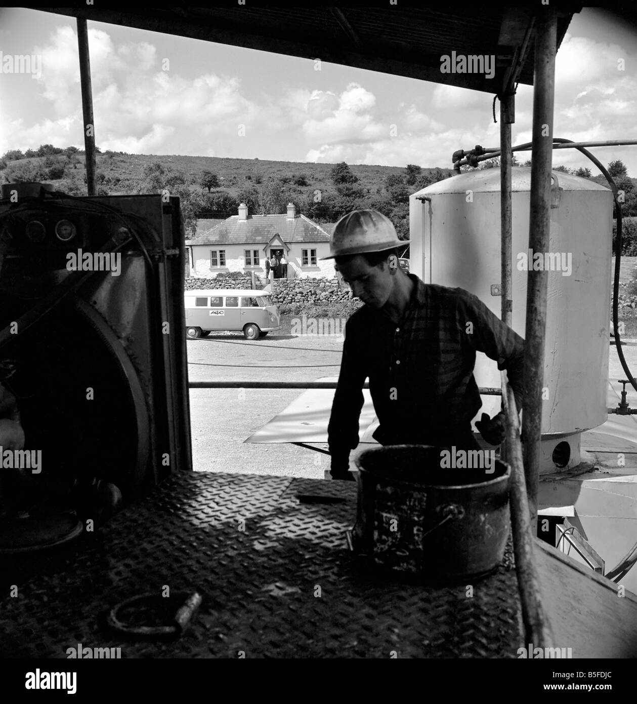 Oil well drilling for oil in Ireland. A farmhouse on the roadside has a ...