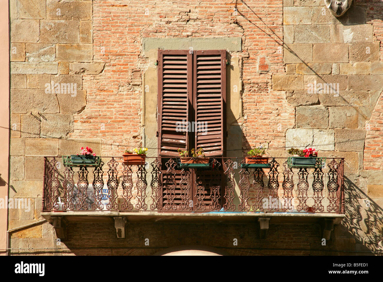 Detail of wrought iron balcony with louvre doors and flowerpots on old ...
