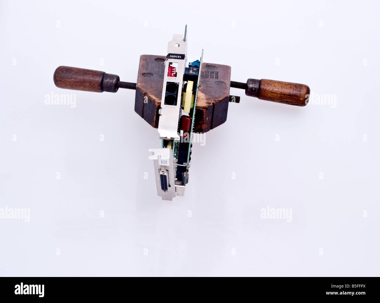 Old antique wooden hand clamp holding a computer circuit board card ...