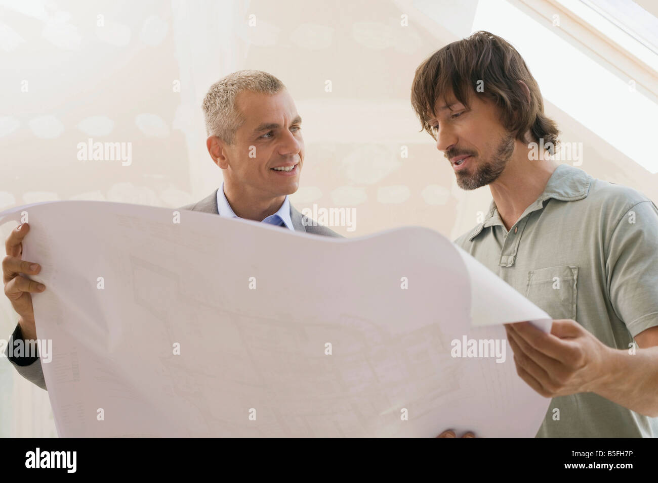 Two men looking at construction plan, portrait Stock Photo - Alamy