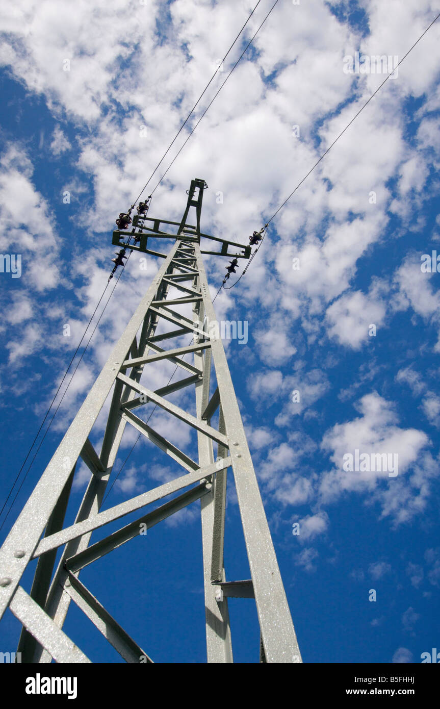 A small gray power pylon and its wires under a deep blue sky with white ...