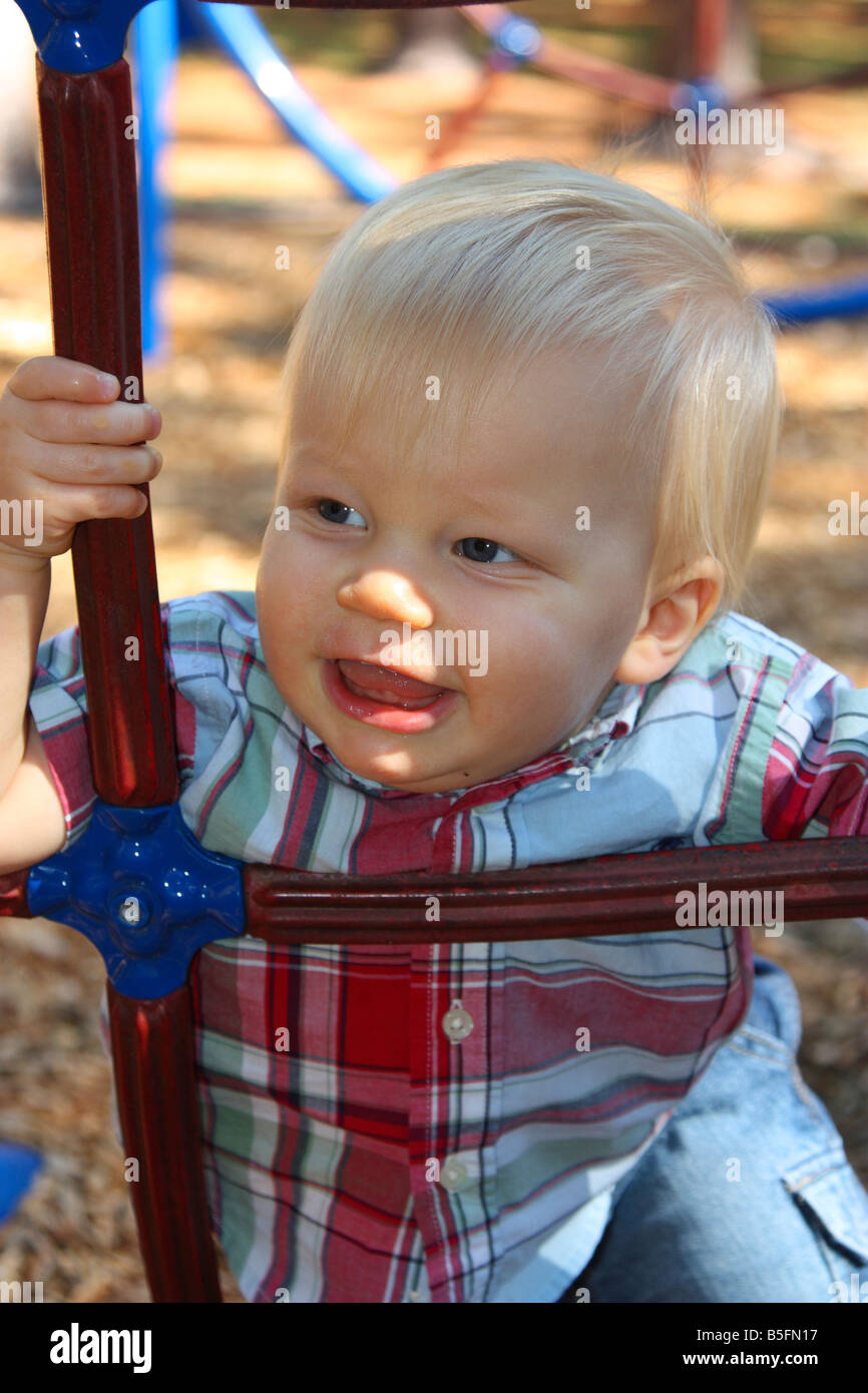 Stock photo of a toddler playing on bars in a playground Stock Photo ...