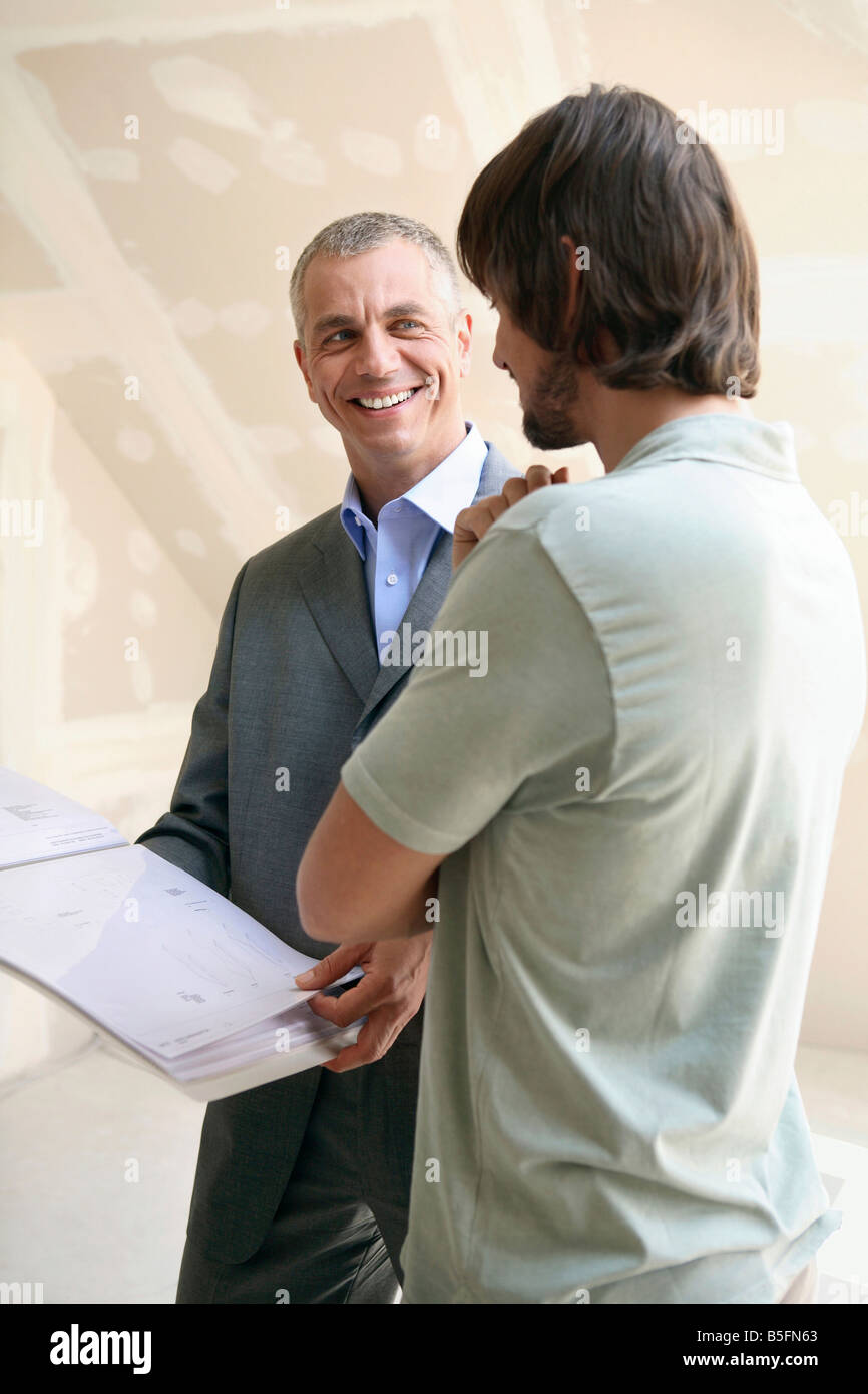 Two men looking at construction plan Stock Photo - Alamy