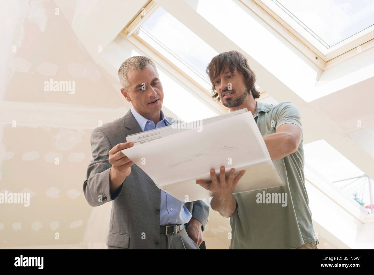 Two men looking at construction plan Stock Photo - Alamy