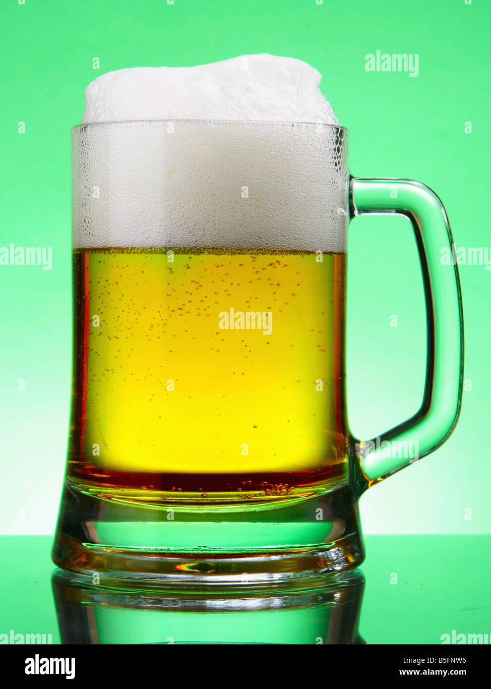 Mug of beer with froth over green background Stock Photo - Alamy