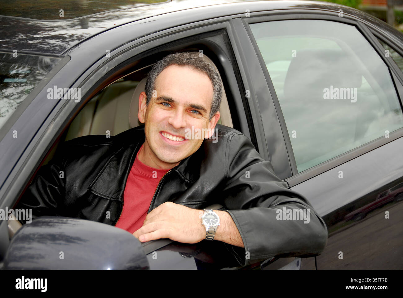 Smiling man looking from a car window Stock Photo - Alamy