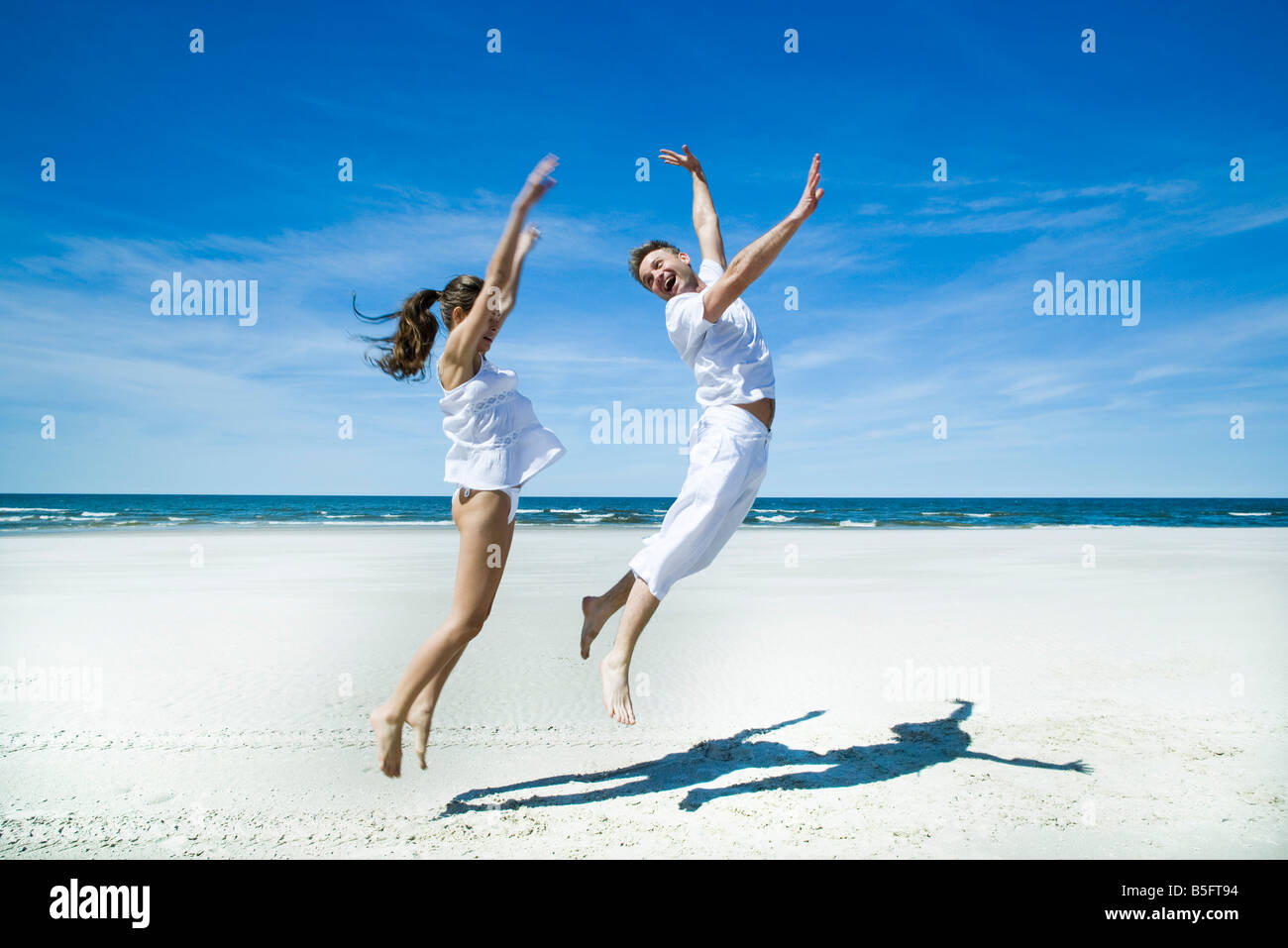 couple jumping on beach Stock Photo - Alamy