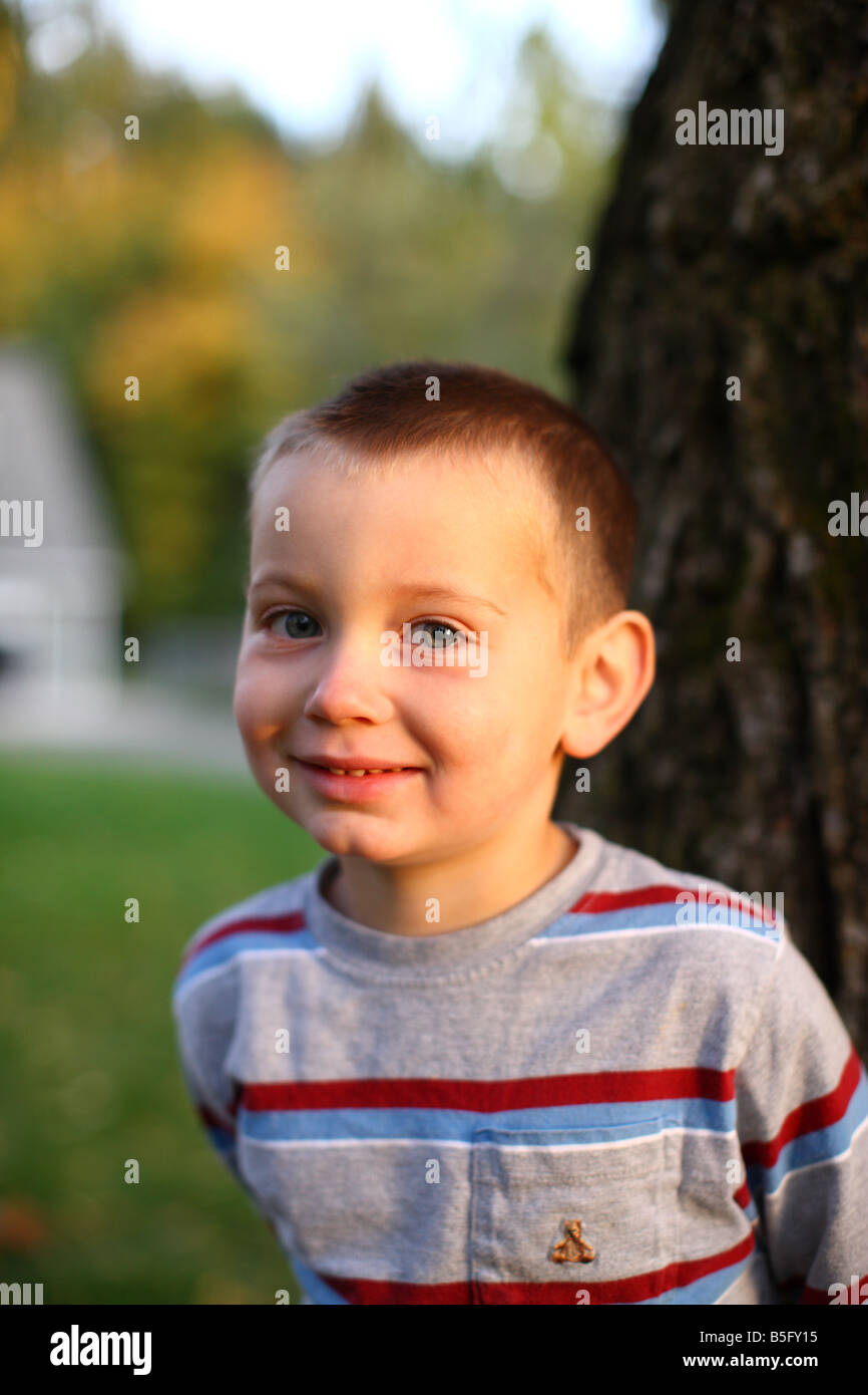 Portrait of young boy standing by tree Stock Photo - Alamy