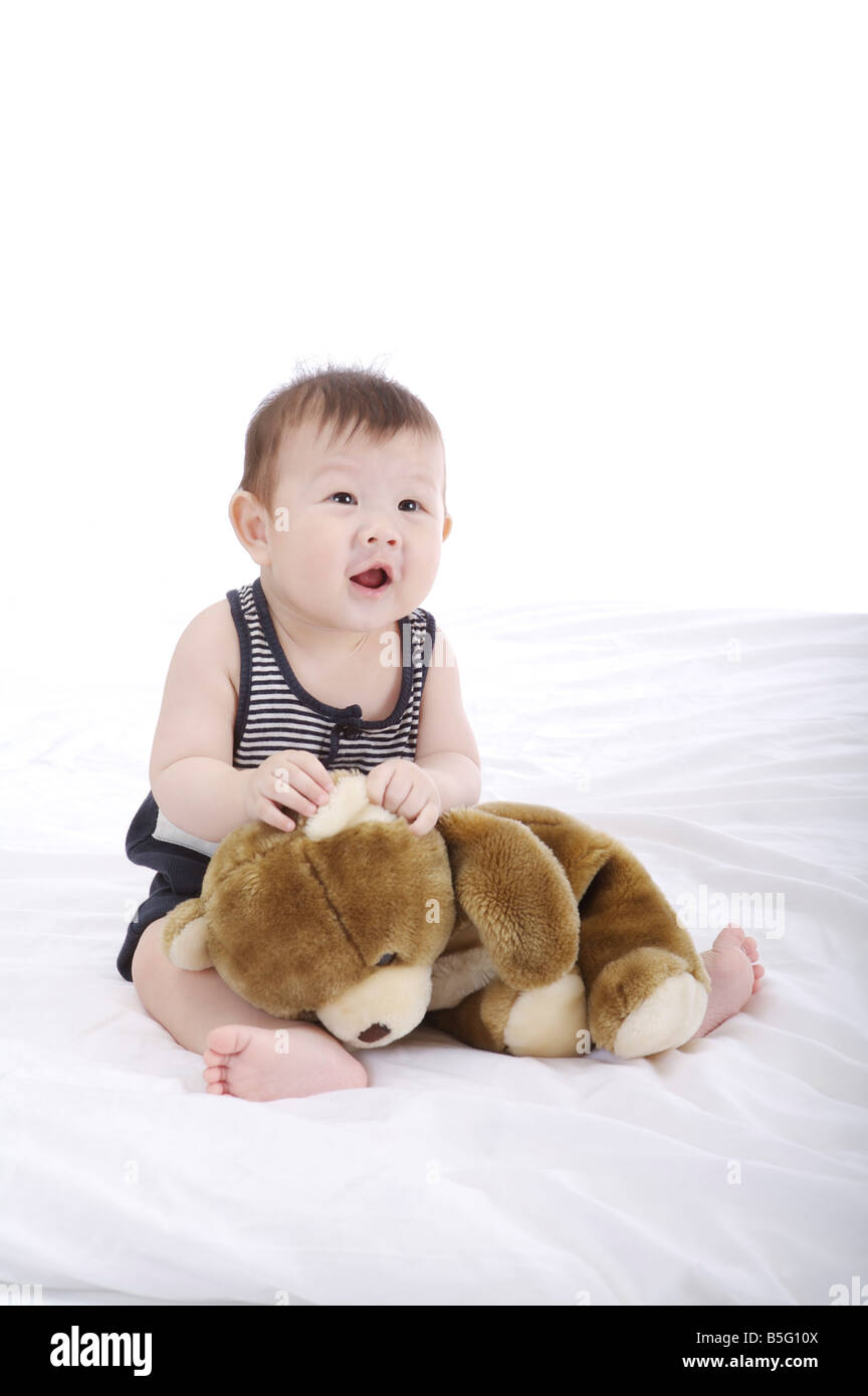 Baby boy sitting upright, playing with a brown teddy bear Stock Photo ...