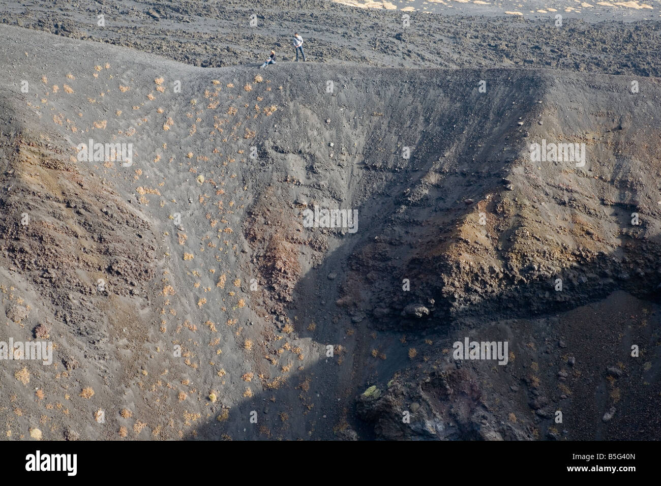 Two people on the rim of a volcanic crater on Mt. Etna volcano Stock ...