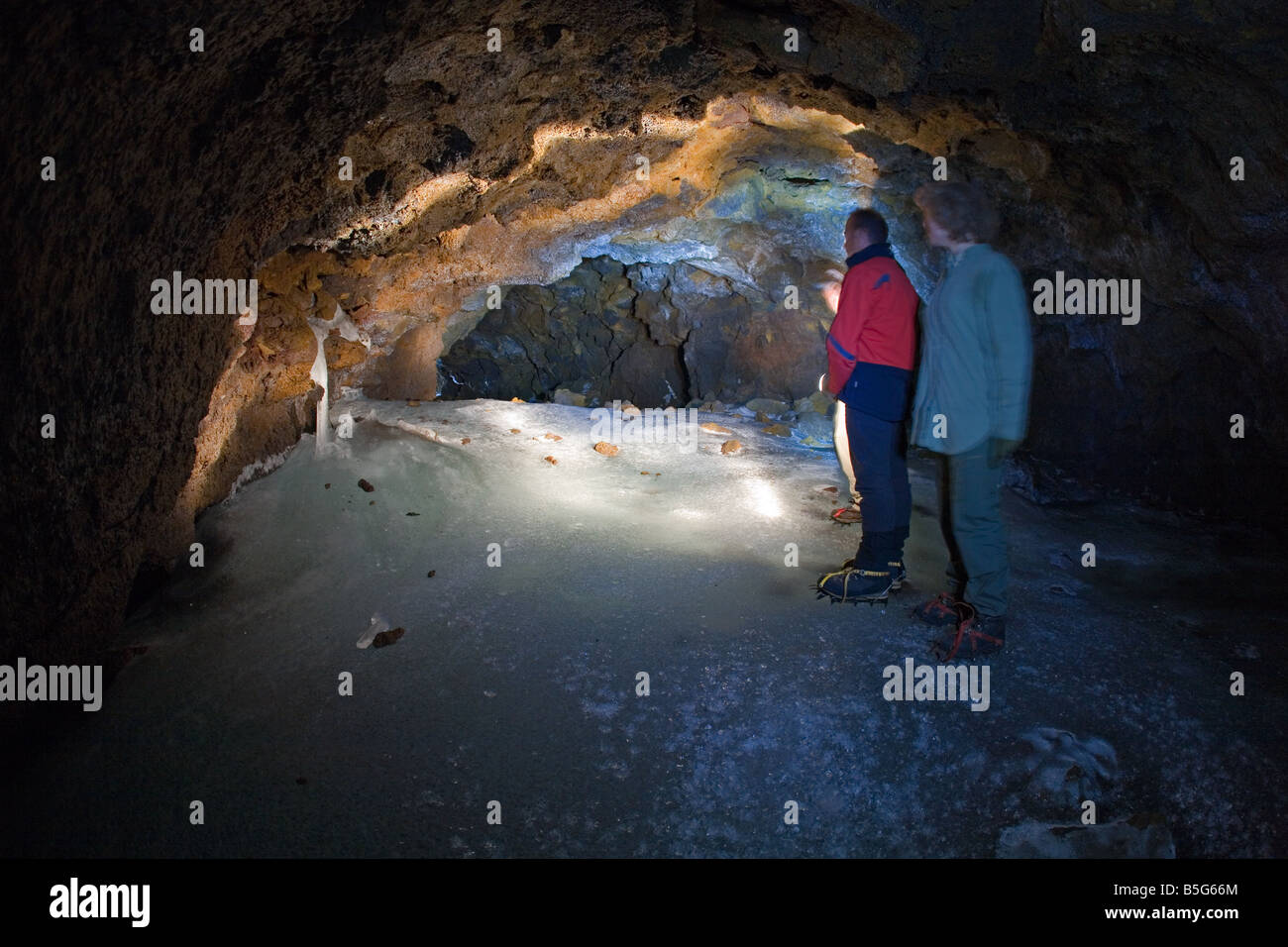 Two people inside the ice-filled lava cave "Grotta del Gelo" on Etna ...
