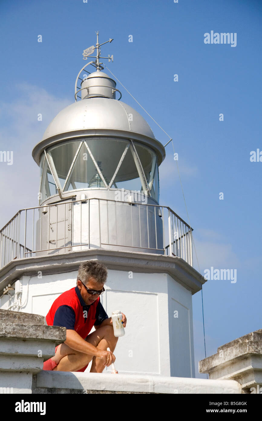 Man painting a lighthouse in the town of Llanes Asturias Spain Stock ...
