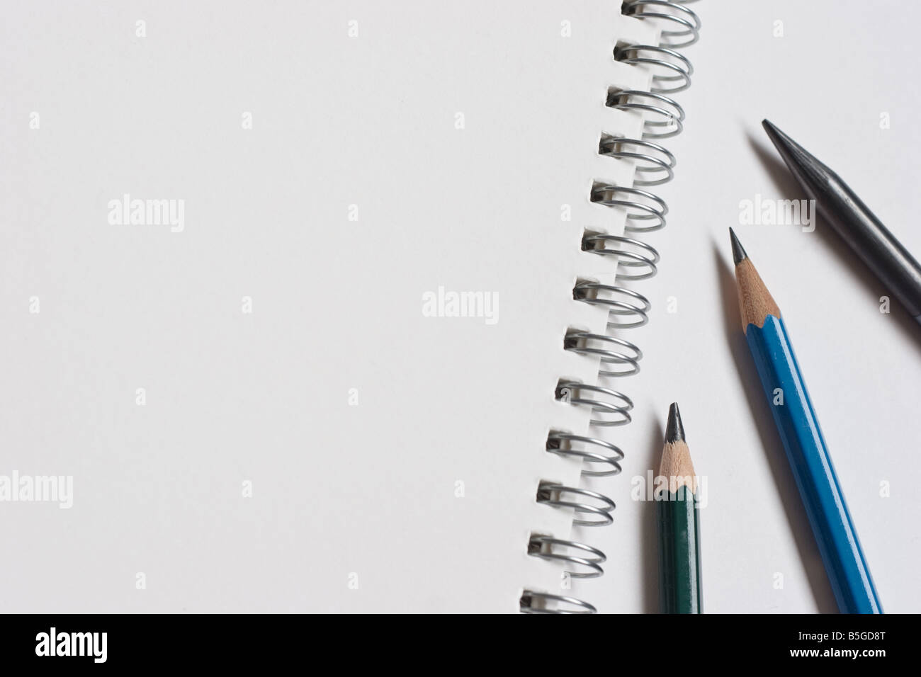 close up photograph of a clean white sketch pad and artists pencils ...