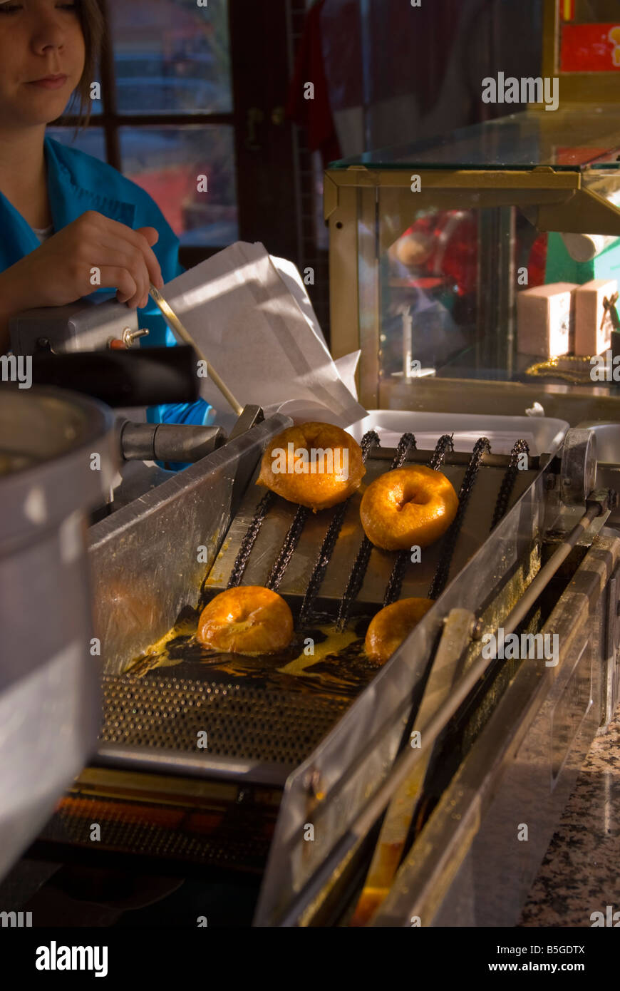 Fresh hot donuts coming out of the donut machine ready to be bagged and ...