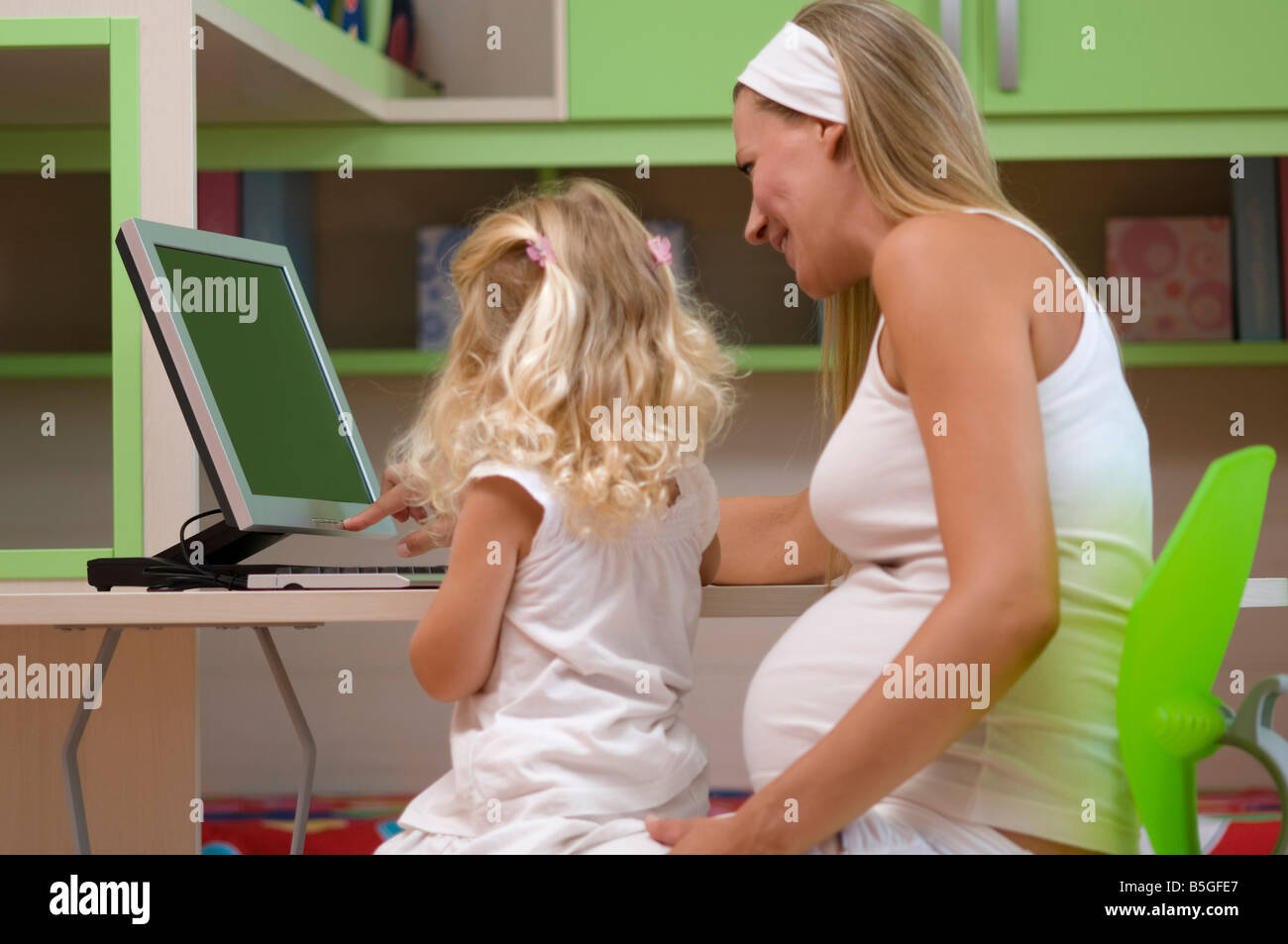 Pregnant mother and daughter (3-4) using computer Stock Photo - Alamy