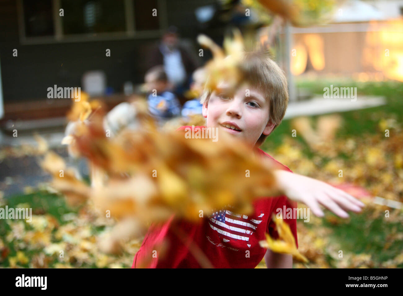 Boy throwing leaves at camera Stock Photo - Alamy
