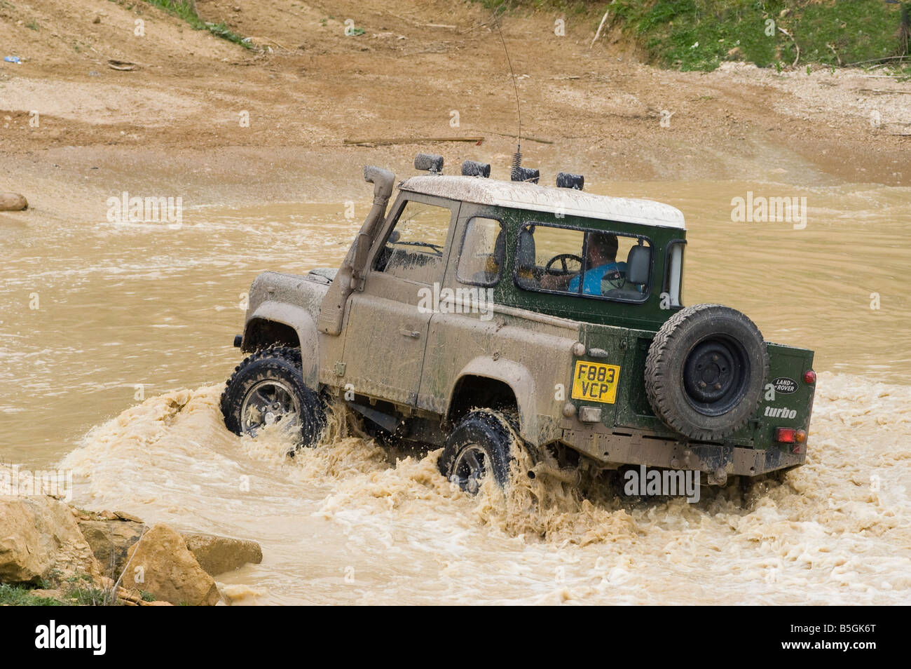 Land Rover defender driving off road through deep muddy water in the UK ...