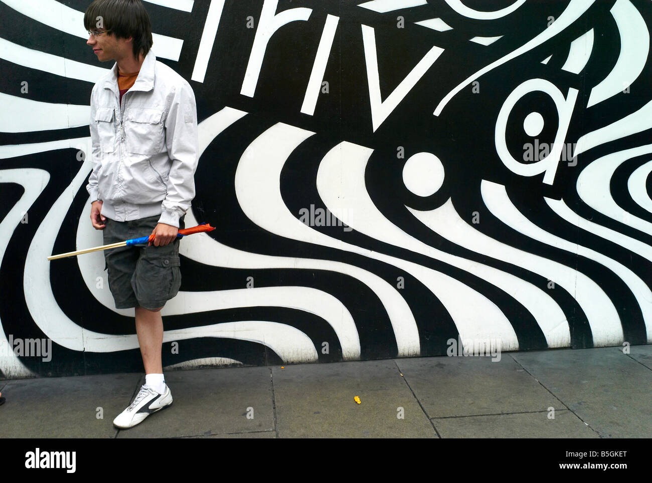 A young man stands against a black and white hoarding that says Trivia ...