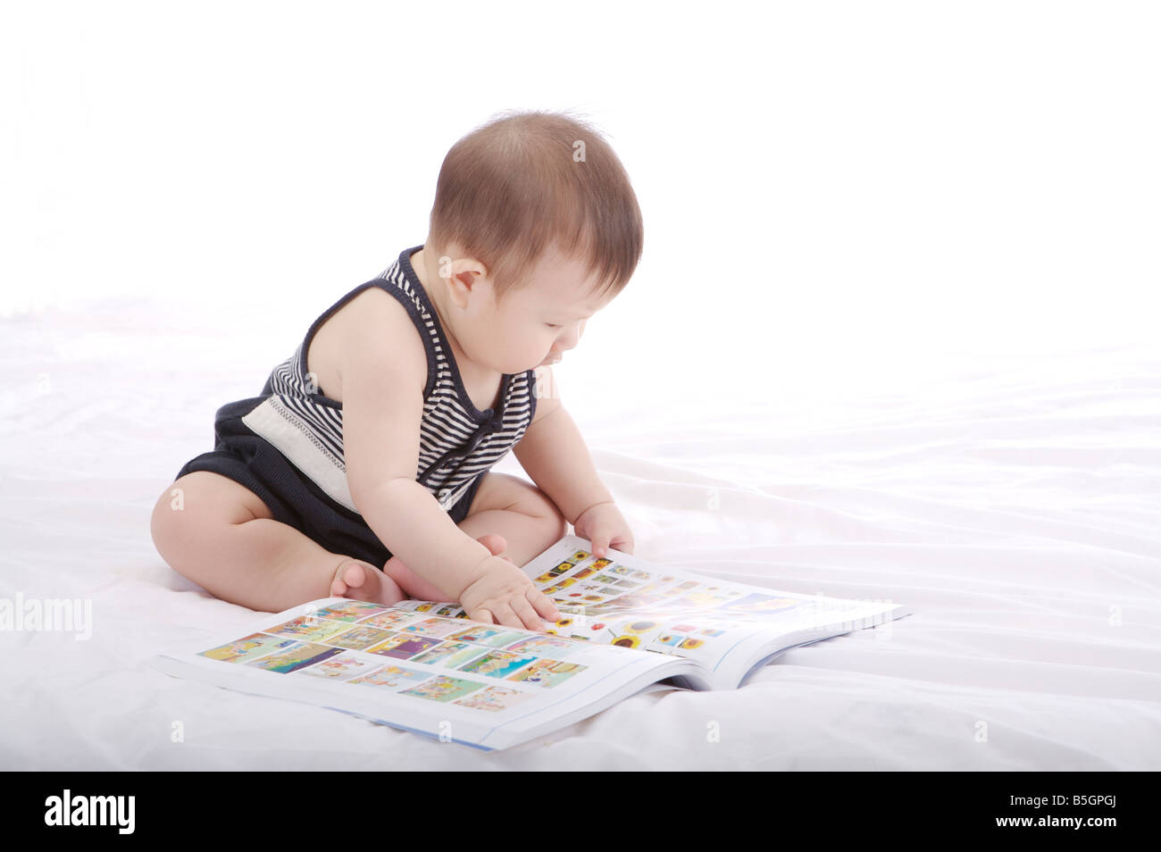 Baby boy sitting, looking at a picture book Stock Photo - Alamy