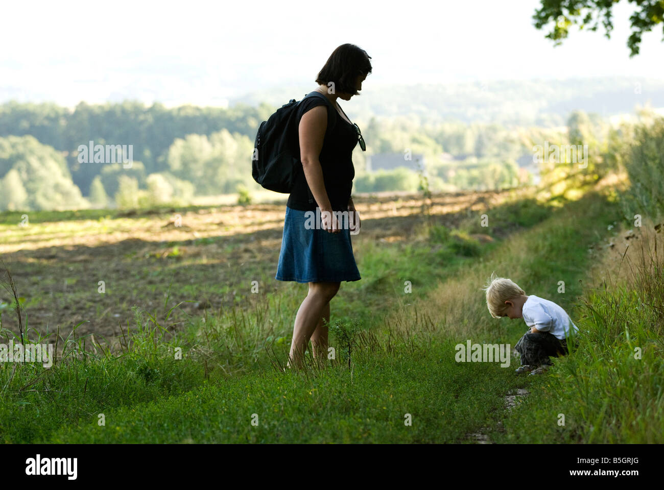 Blond boy standing with mother summer / autumn in plow field near ...