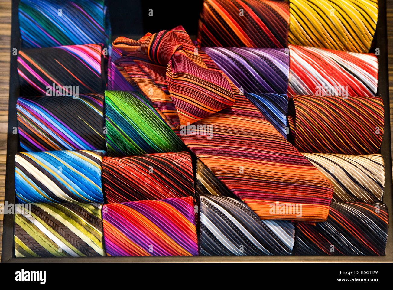 A box with rolled up colorful ties and one unrolled tie Stock Photo - Alamy
