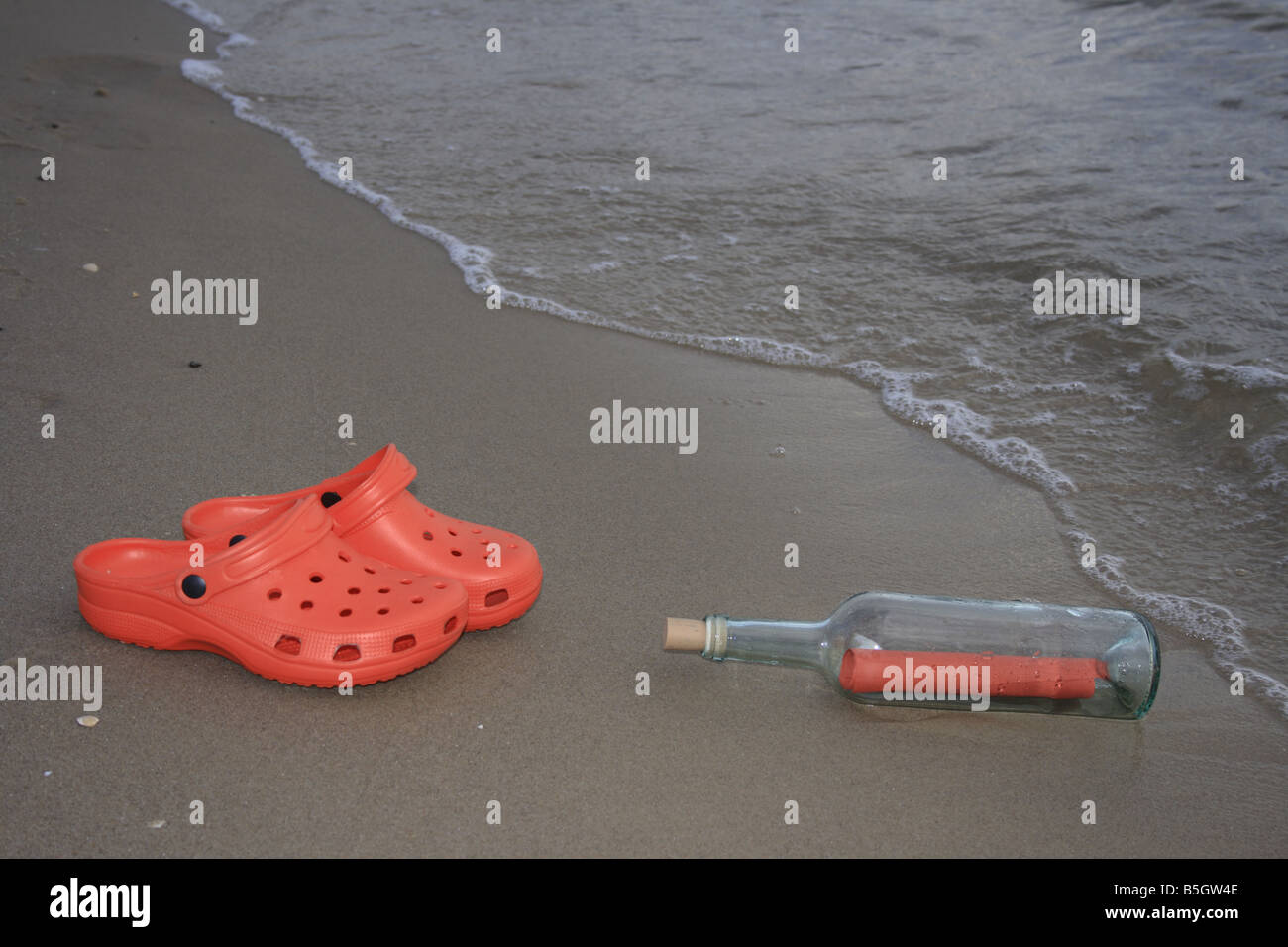 pair of red crocs and red letter as message in a bottle at a sandy ...