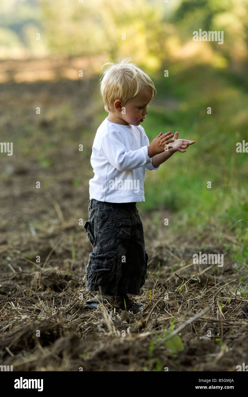 Blond boy standing summer / autumn in plow field Stock Photo - Alamy