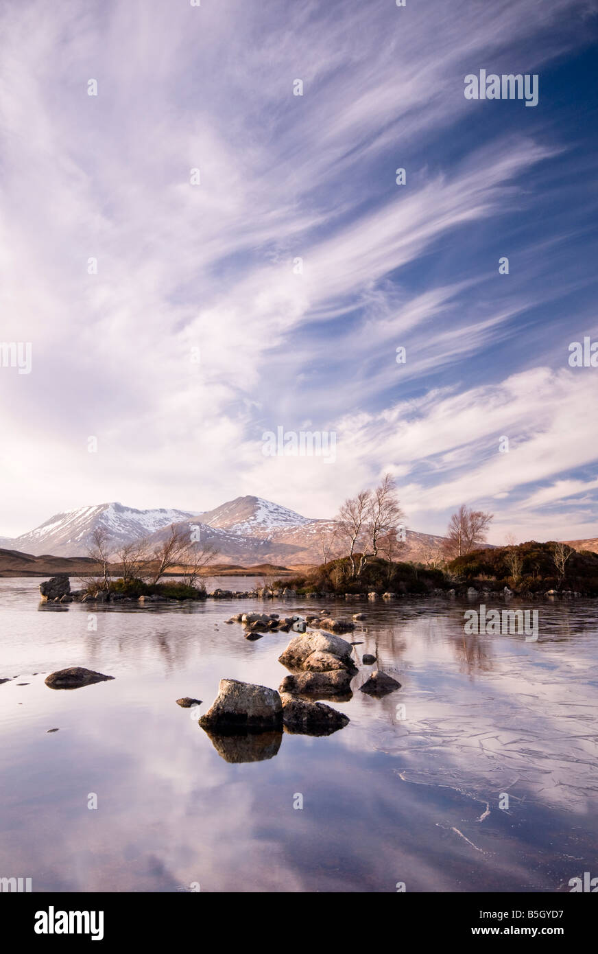High level clouds clear over a frozen loch in the desolate Rannoch Moor ...