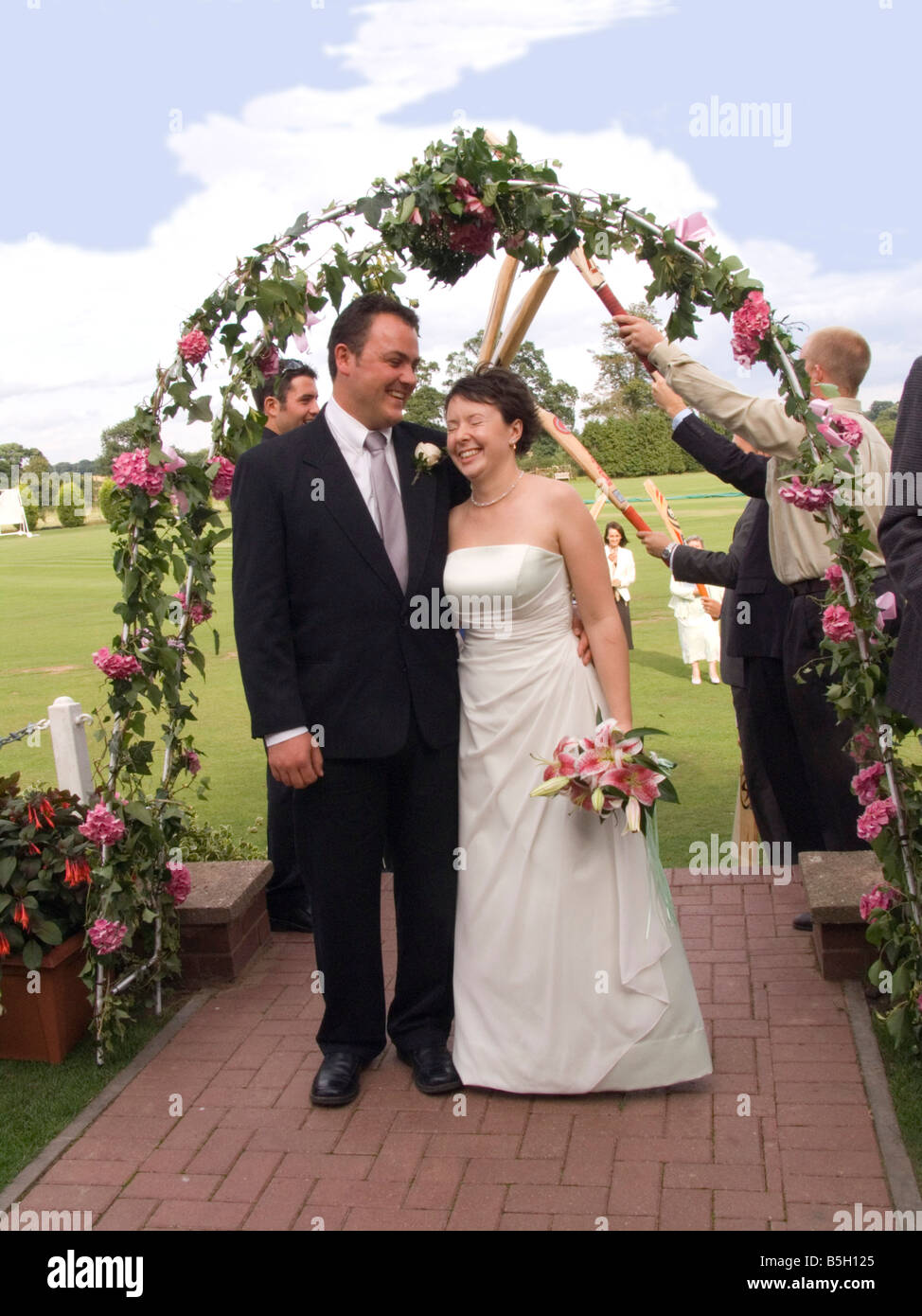 Staffordshire UK August Bride and groom standing under a rose covered ...