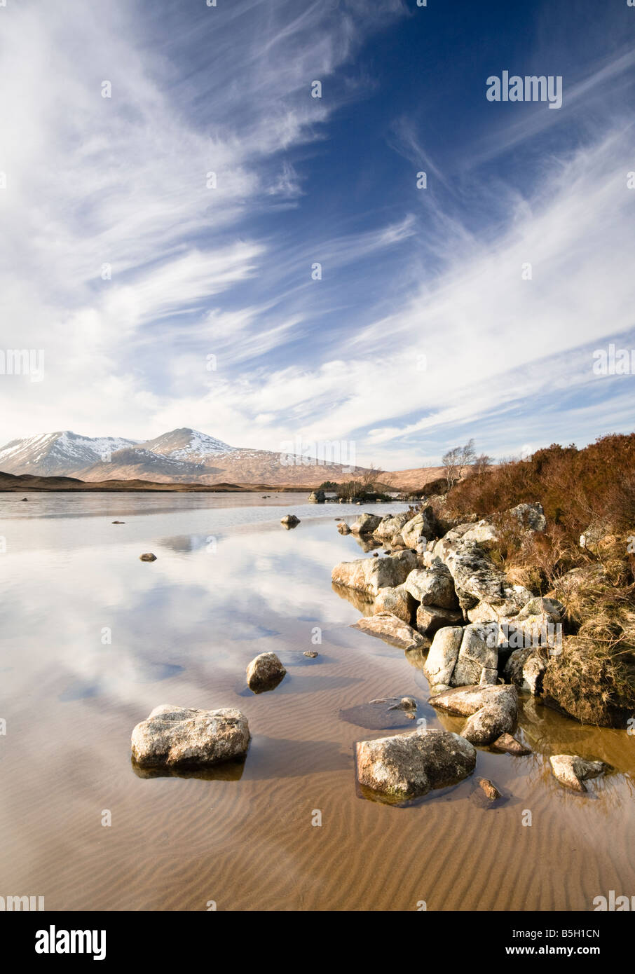 High level clouds clear over a frozen loch in the desolate Rannoch Moor ...