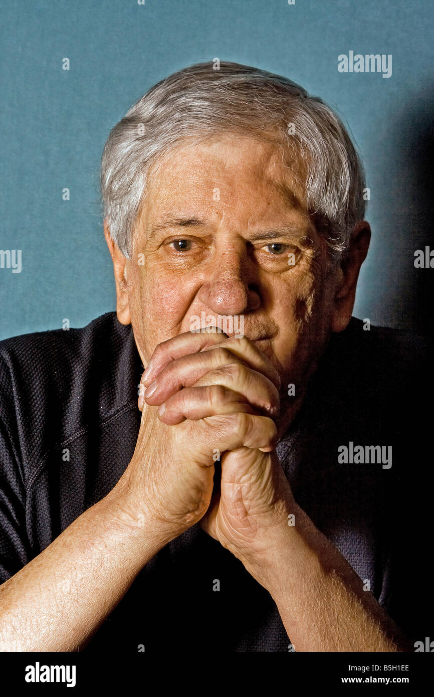 Dramatic portrait of a senior man with his hands in front of his chin ...