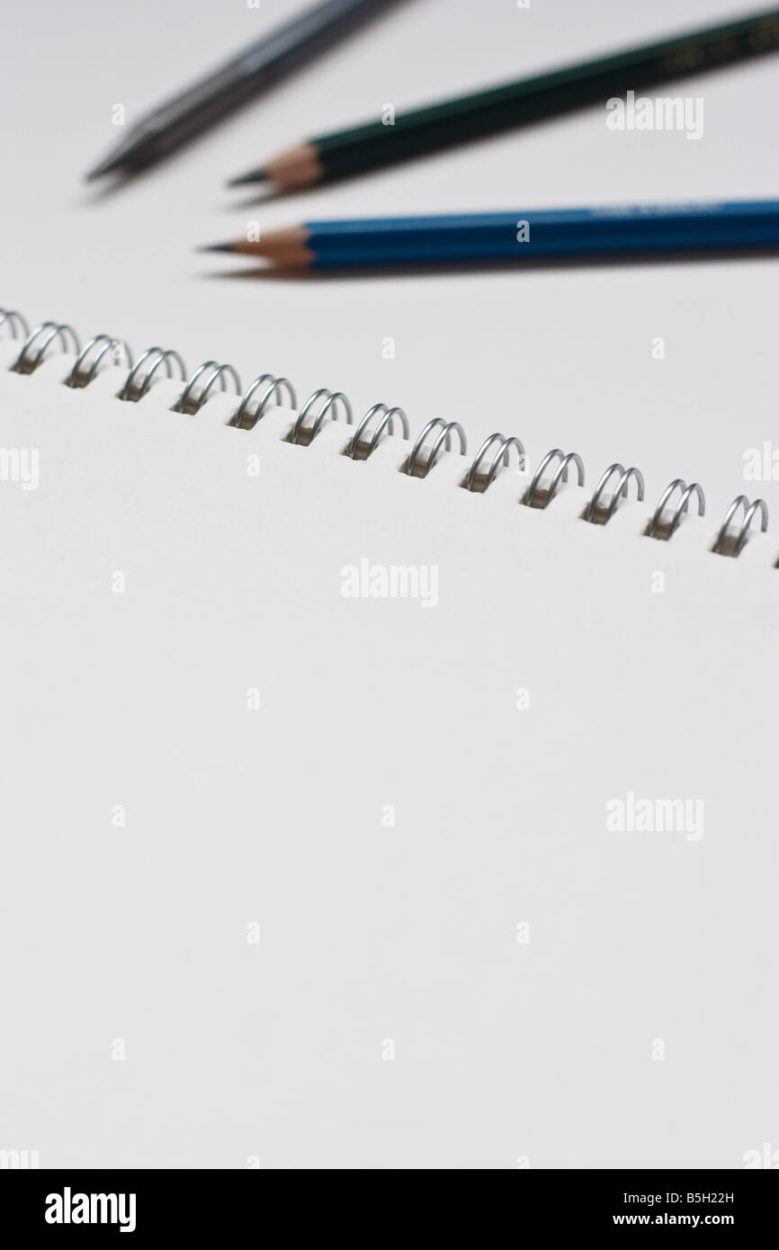 close up photograph of a clean white sketch pad and artists pencils ...