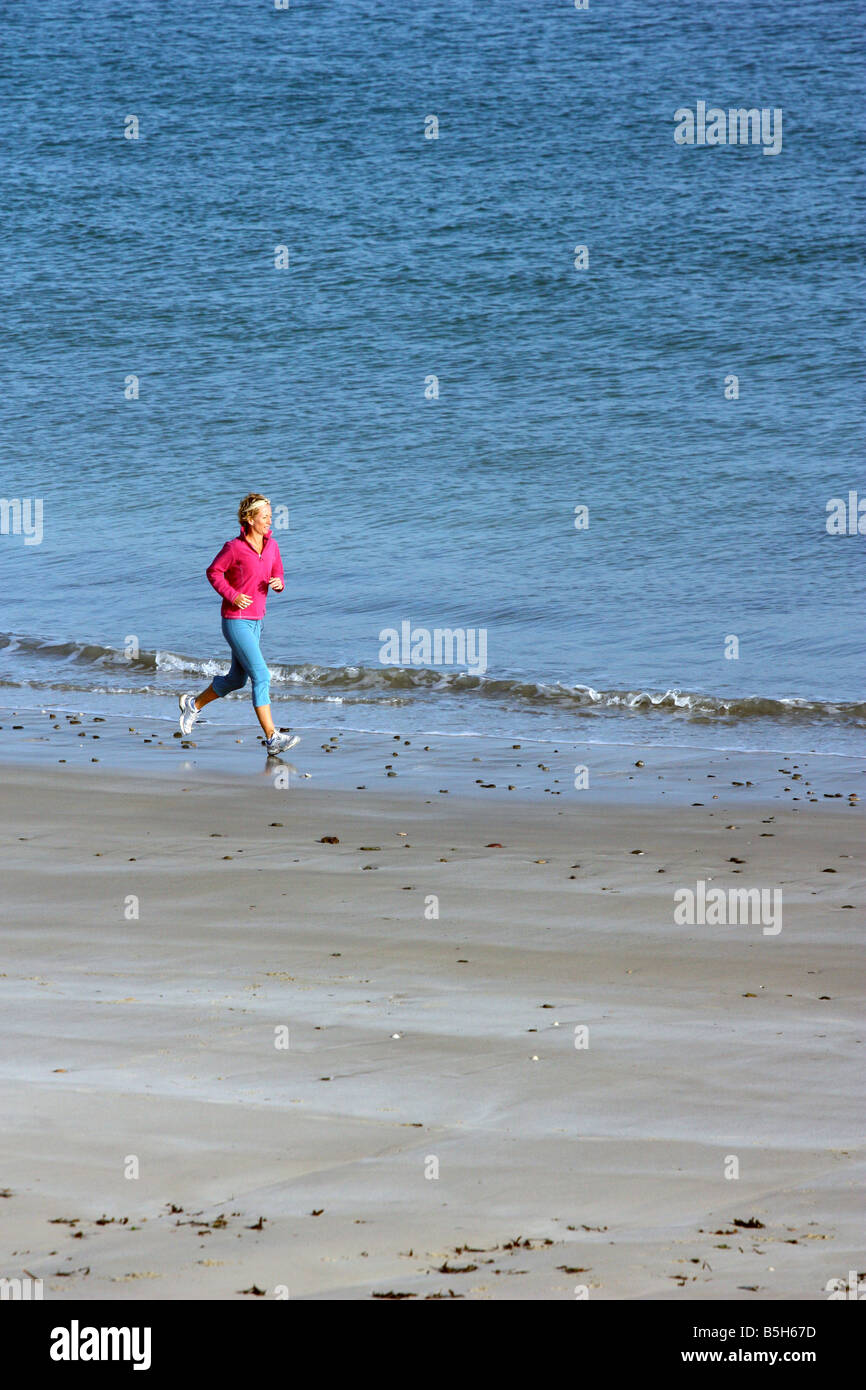 Blonde woman outdoors. Jogging along beach Stock Photo - Alamy