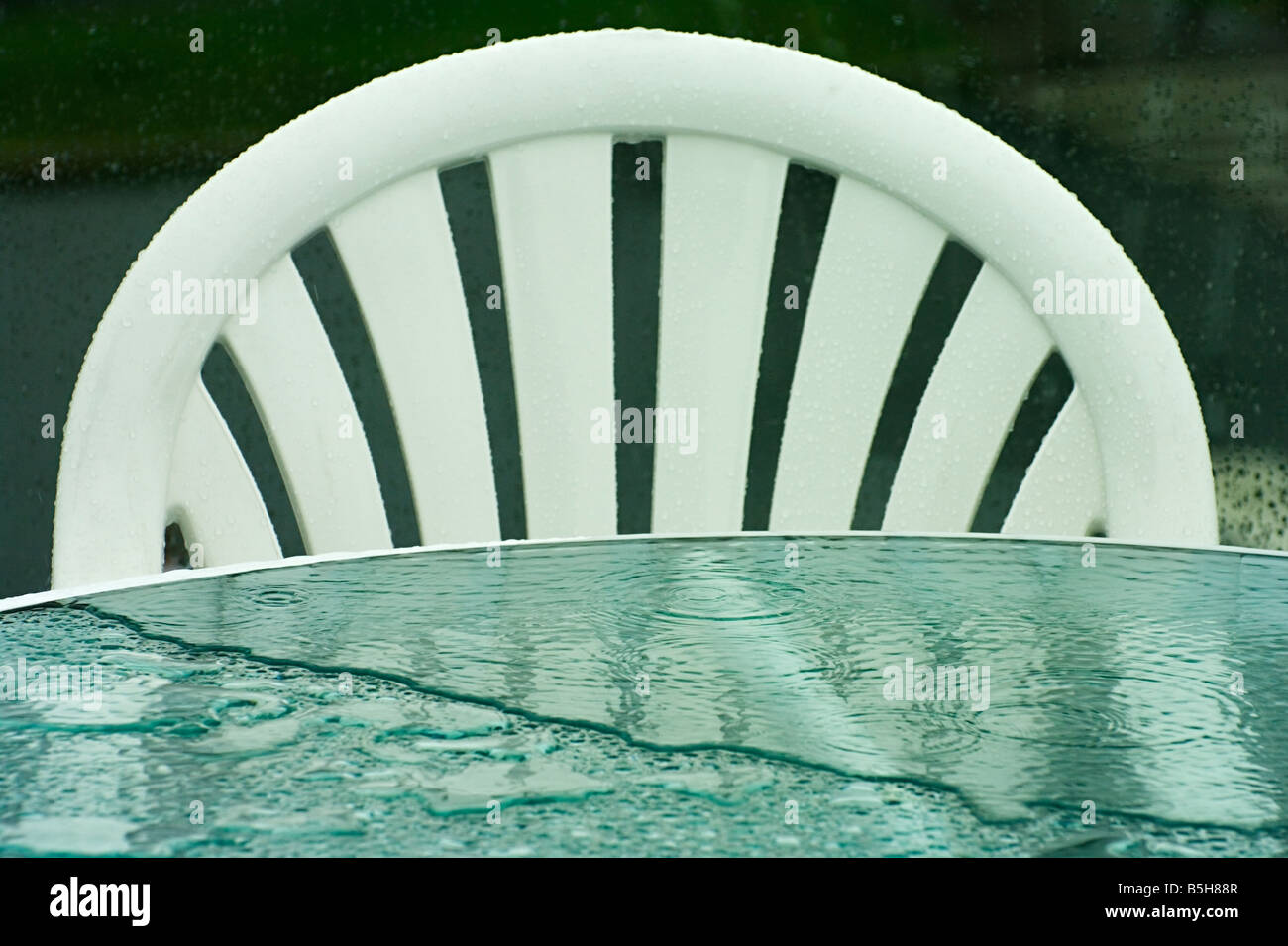 Rain puddle on outdoor glass cafe table with raindrops and slightly ...