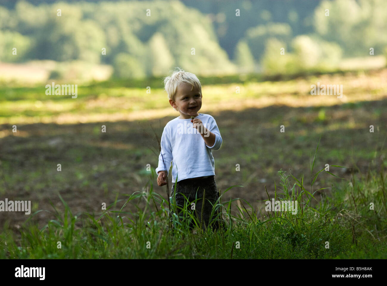 Blond boy standing summer / autumn in plow field Stock Photo - Alamy