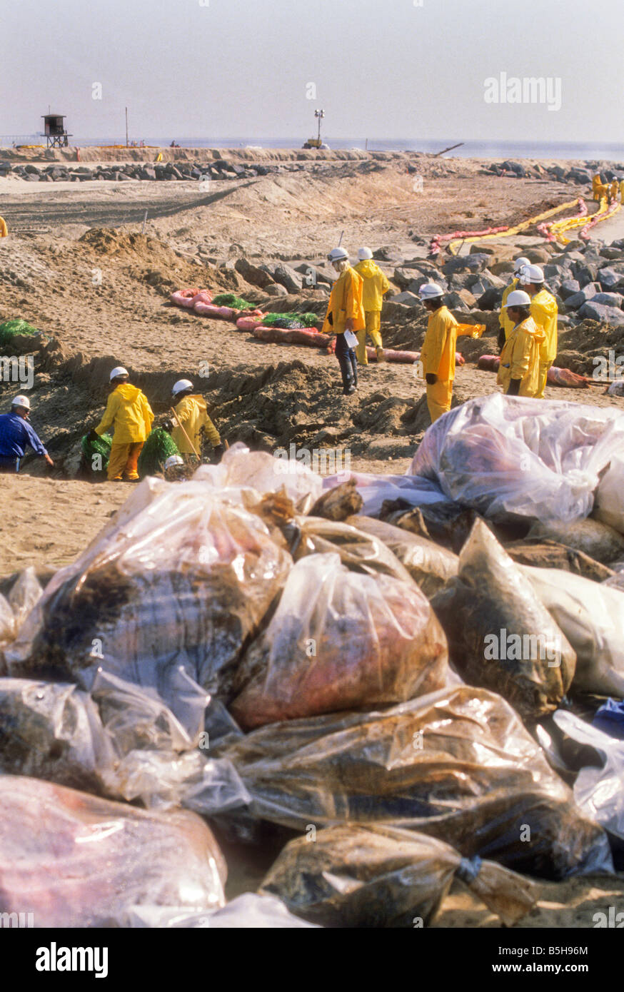 Workers carry a long flexible dam to control an oil spill in California ...