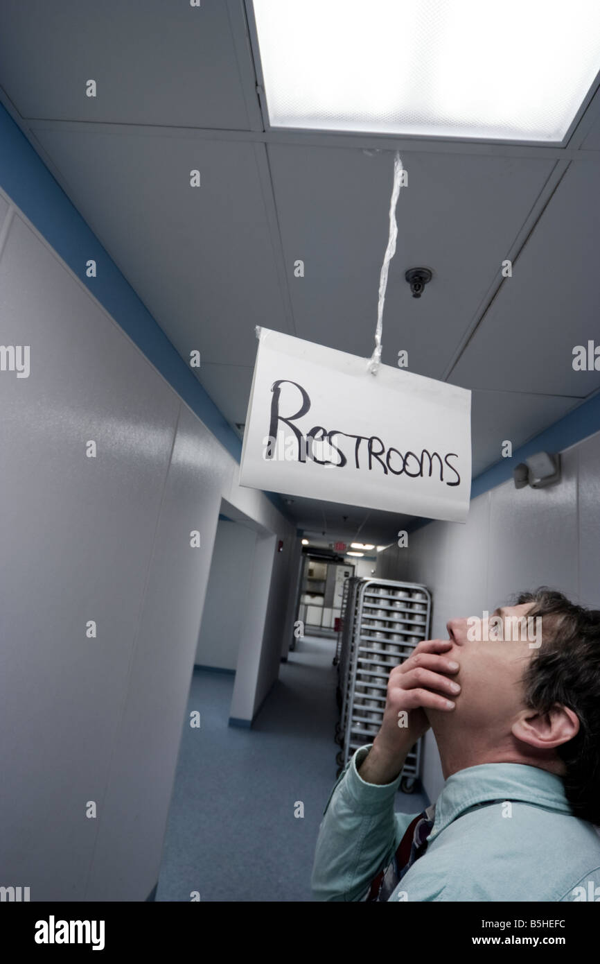 Man looking at a hanging sign in a factory that reads Restrooms MODEL ...