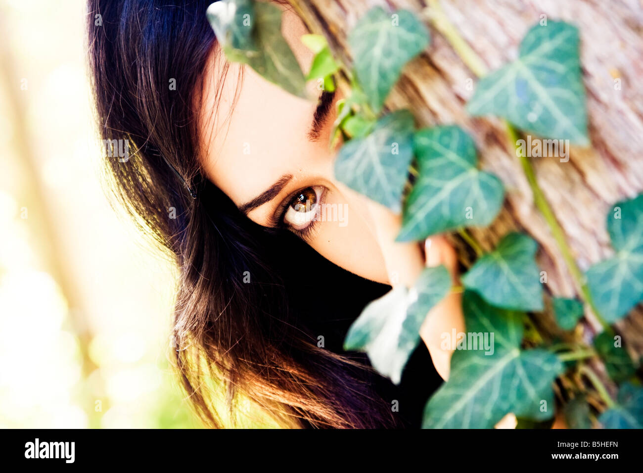 Young beautiful woman observing behind leaves Stock Photo - Alamy