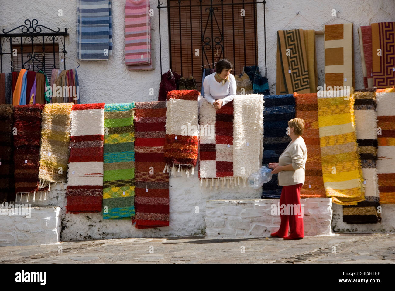 Spanish ladies chatting outside shop selling locally made carpets and ...
